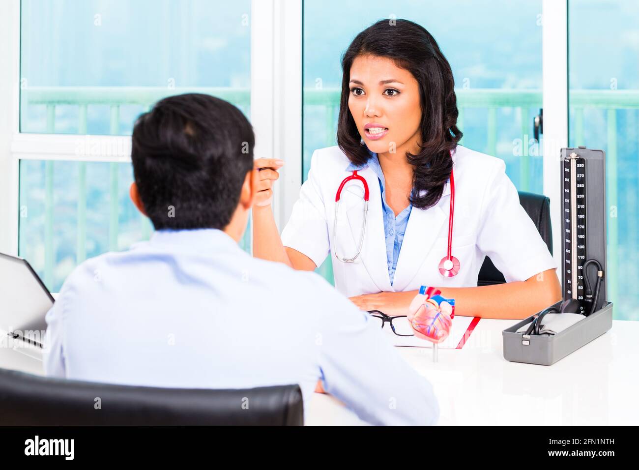 Asian female doctor giving patient medical advice in practice or office ...