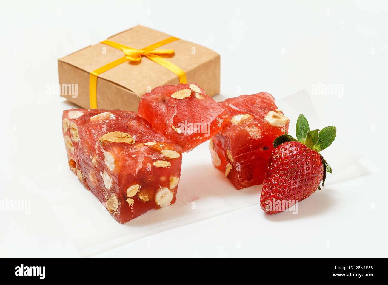 Fruit sweets with nuts, a fresh strawberry and a gift box on the white ...