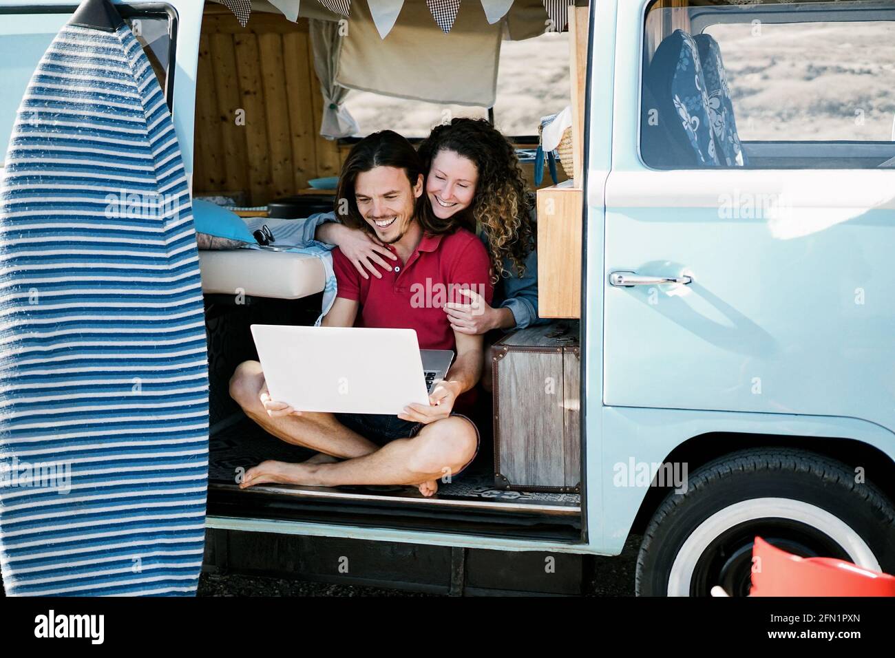 Happy couple using laptop computer inside minivan during road trip ...