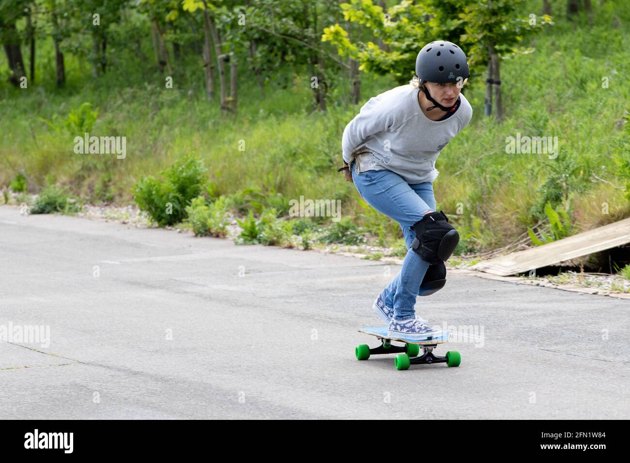 Young woman skateboarder in an aerodynamic position going down hill ...