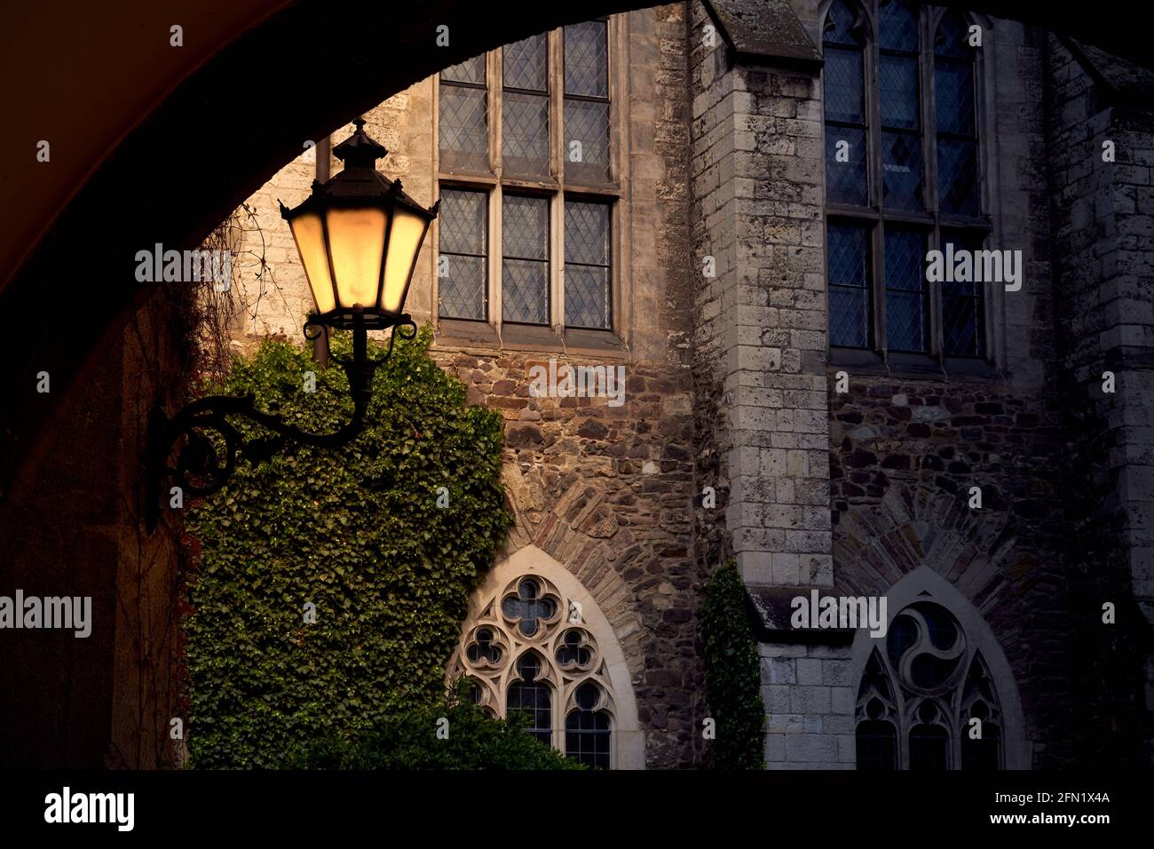 Shining yellow lantern in front of medieval sacral building with high ...