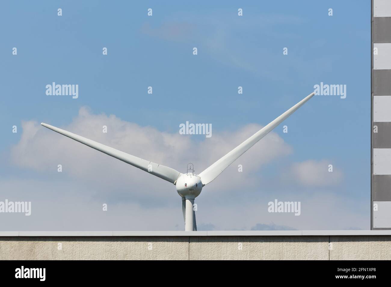 The head of a wind turbine is framed on two sides by buildings and ...