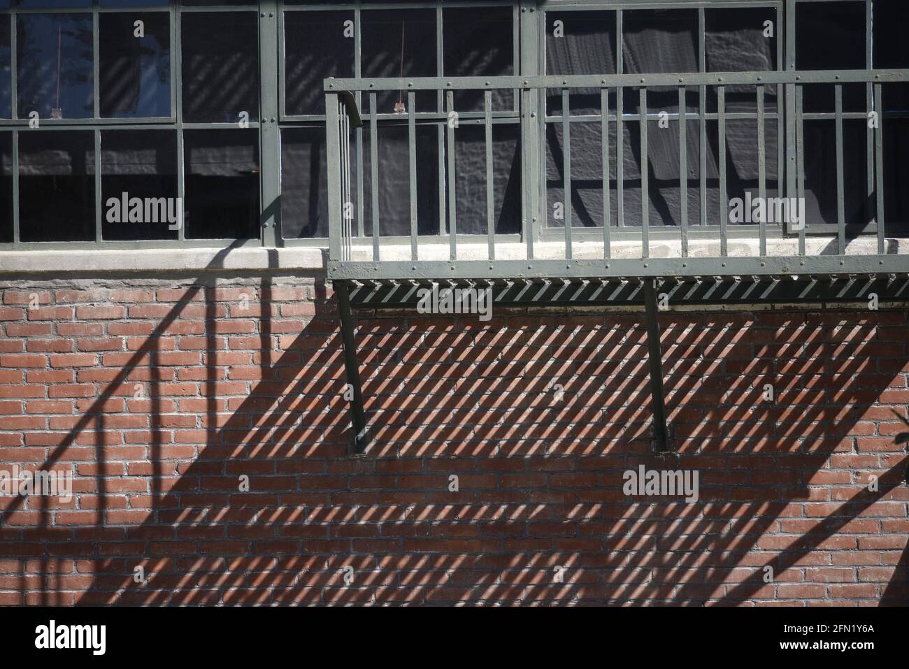 Old Colonial building with the iron railing shadow on the brick facade ...