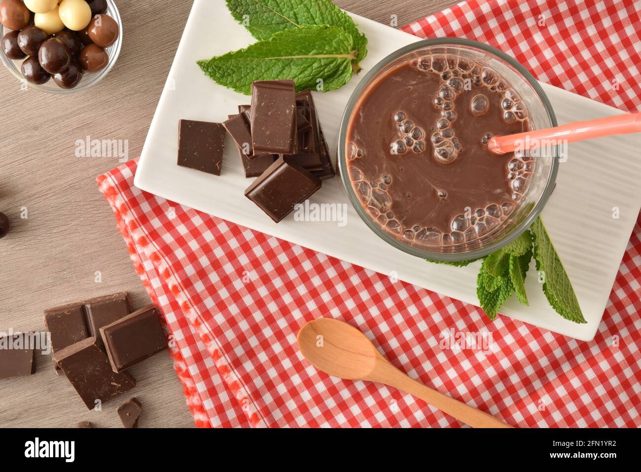 Glass with milk chocolate shake on plate with balls and chocolate ...