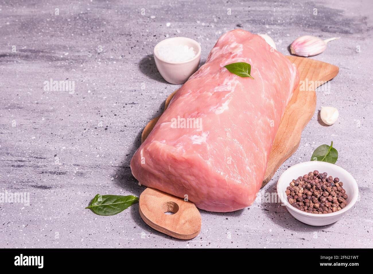 Raw pork loin on a chopping board. Fresh meat, spices, sea salt, leaves ...