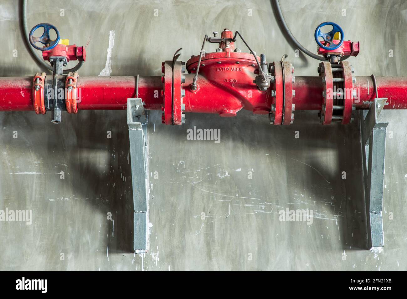 Red water or gas pipeline with gate pressure valve on concrete wall ...