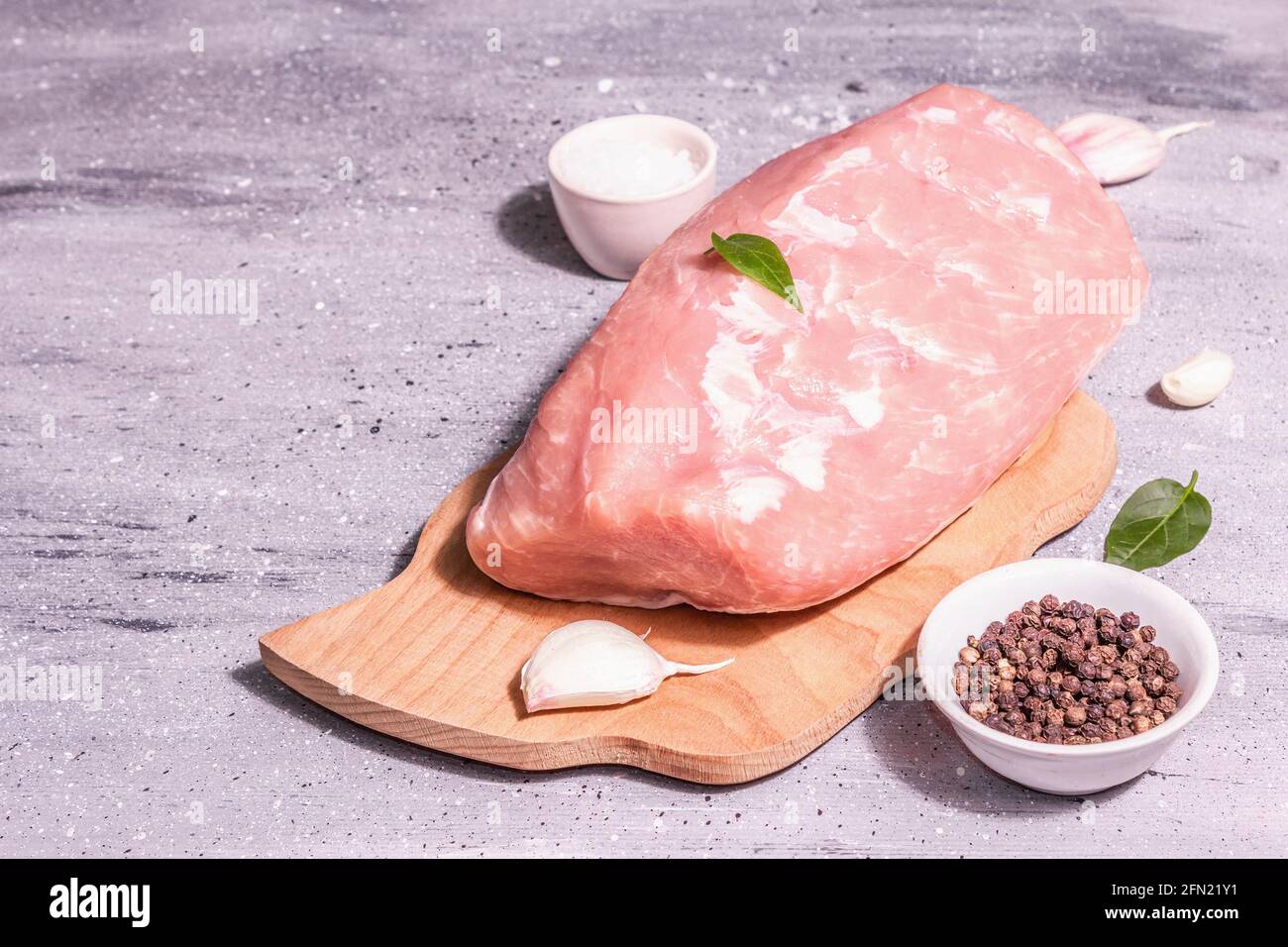 Raw pork loin on a chopping board. Fresh meat, spices, sea salt, leaves ...