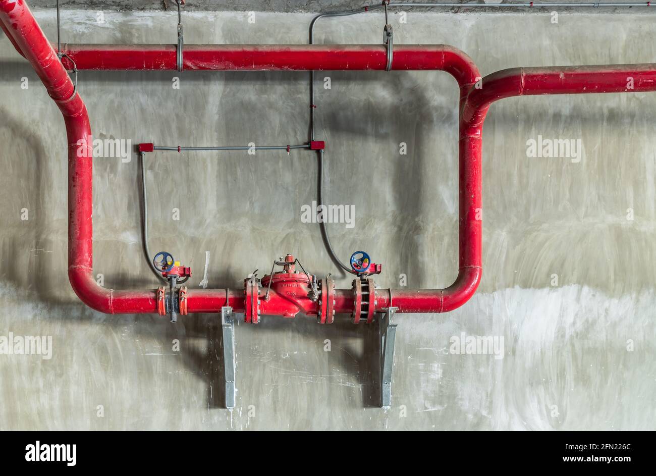Red water or gas pipeline with gate pressure valve on concrete wall ...