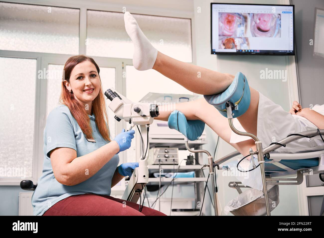 Portrait Of Gynecologist While Examining Patient With Colposcope Woman Sitting In Gynecological