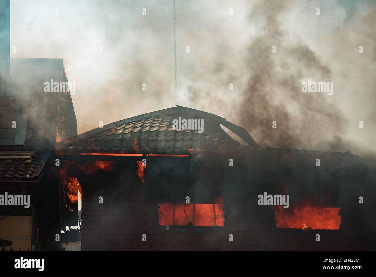 a team of rescuers extinguish a fire in the house. firefighters pour ...