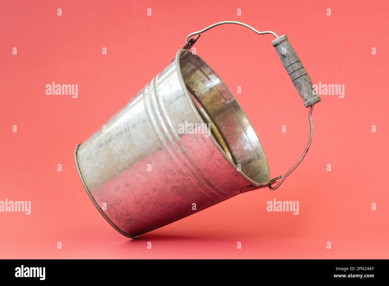 Empty metal bucket falling on pink background Stock Photo - Alamy