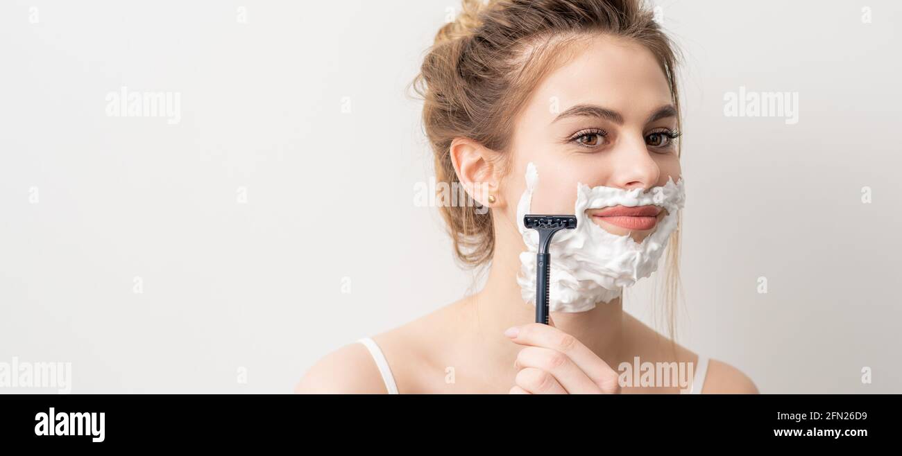 Beautiful young caucasian smiling woman shaving her face with razor on ...