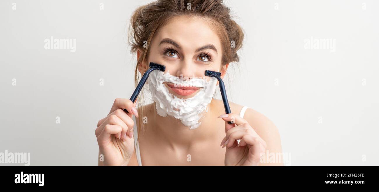 Beautiful young caucasian smiling woman shaving her face with razor ...