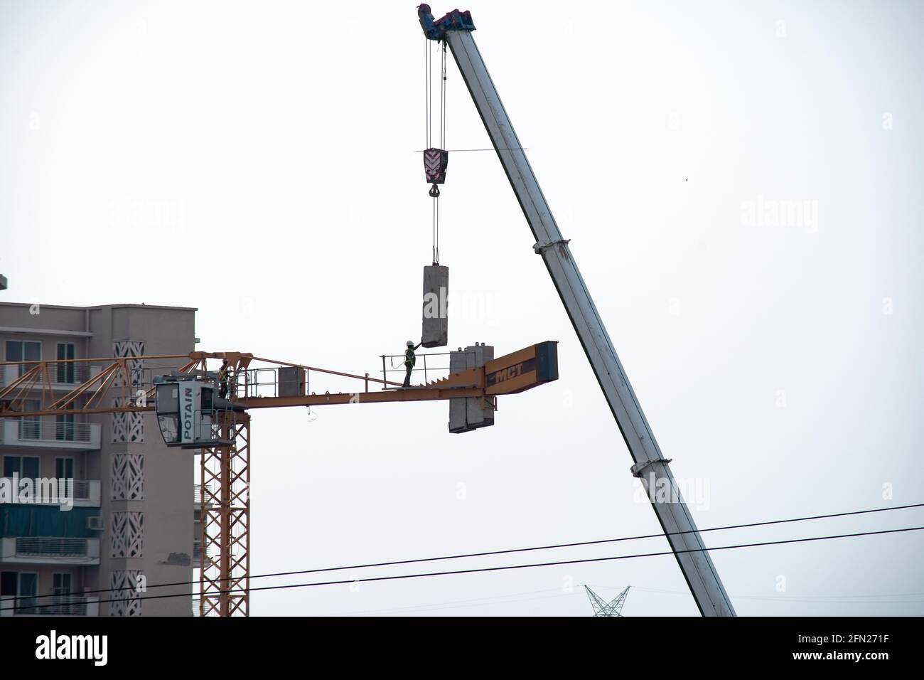 construction crane being built using a secondary crane shot against ...
