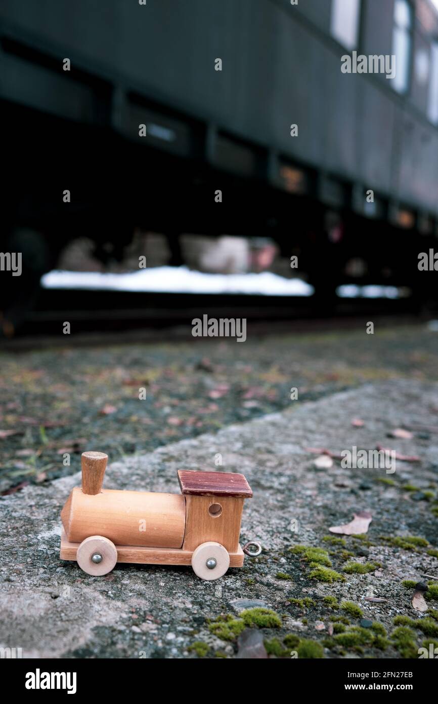 small wooden toy train on rail tracks with historic big train in the ...