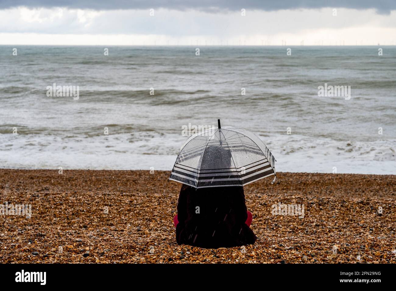 A Young Woman Sitting In The Rain On Brighton Beach, Brighton, East ...