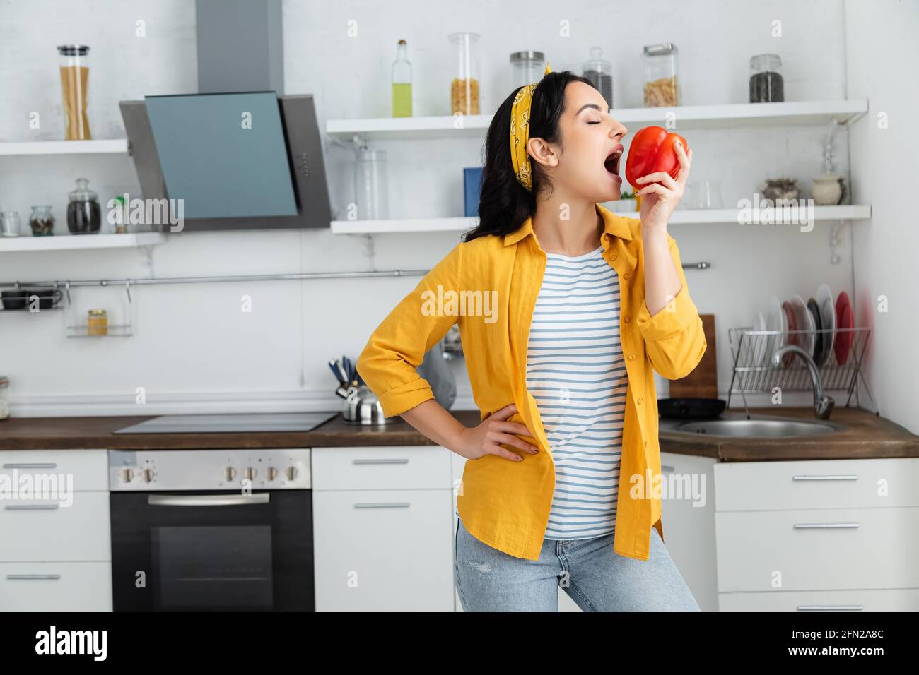 young brunette woman with closed eyes biting red bell pepper Stock ...