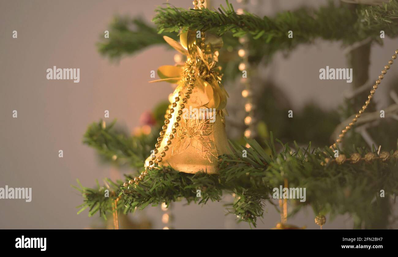 Closeup of a golden bell Christmas tree ornament hanging from the tree ...