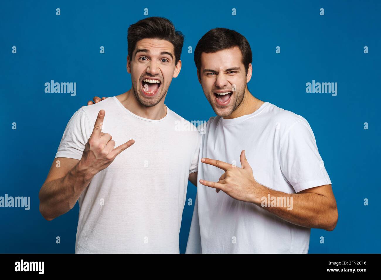 Excited unshaven two guys screaming while showing horns signs isolated ...