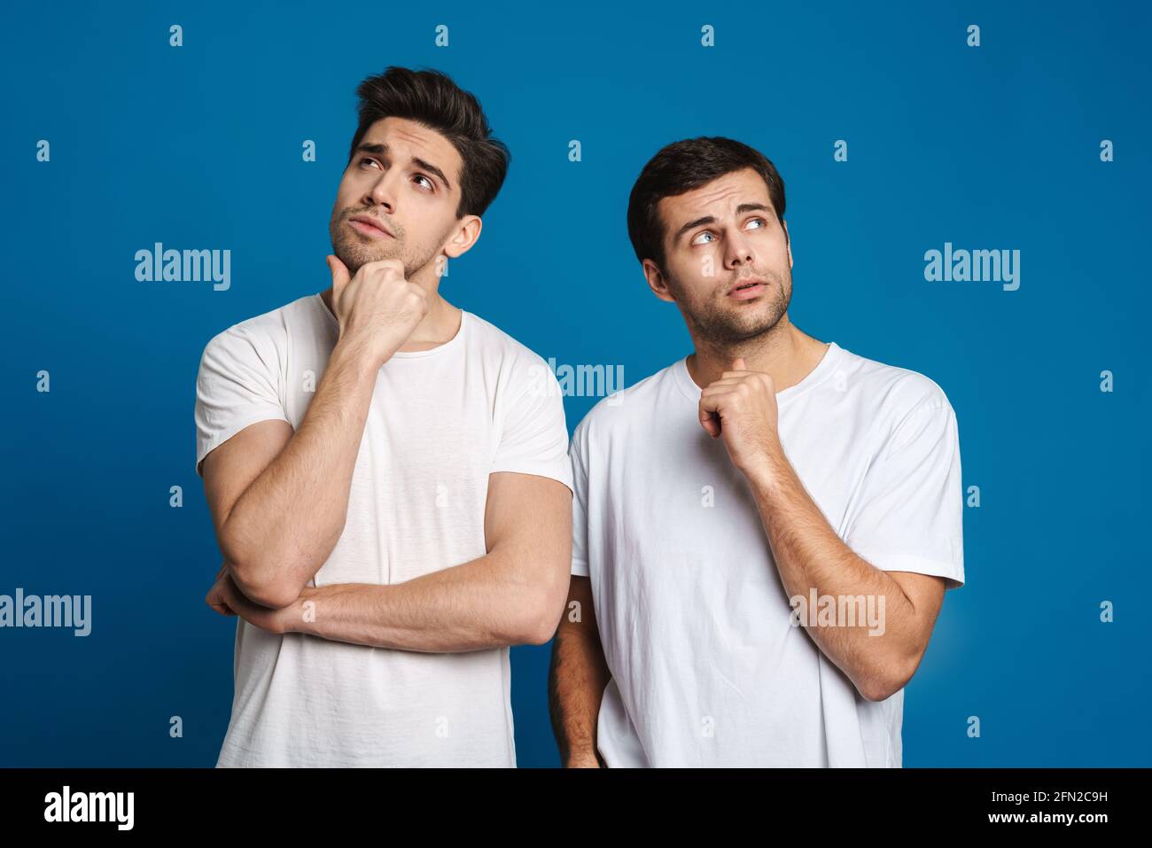 Thinking handsome guys posing and looking at opposite sides isolated ...