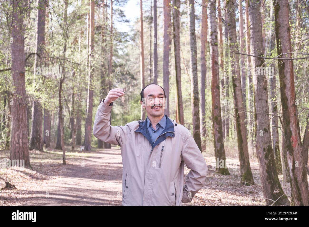 Half-length portrait of senior Asian man reciting poetry in forest park ...