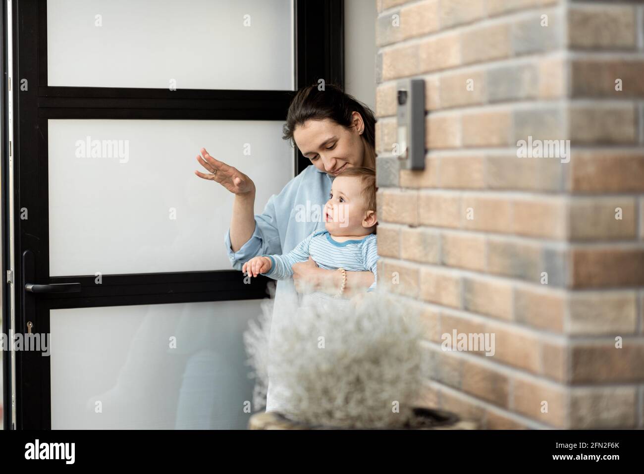 Housewife with newborn baby staying in front of entrance door and ...