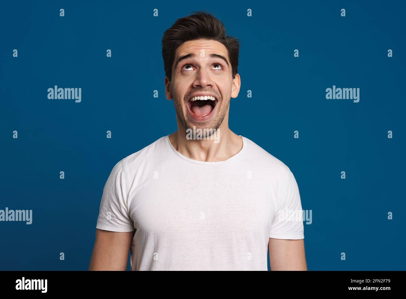 Excited unshaven guy expressing surprise on camera isolated over blue ...