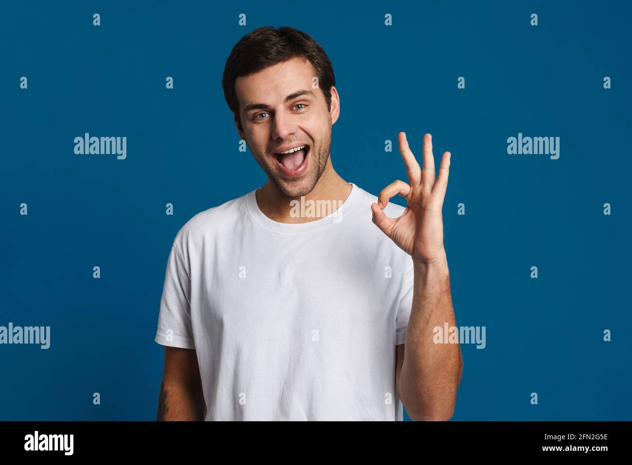 Happy unshaven guy smiling and showing ok sign at camera isolated over ...