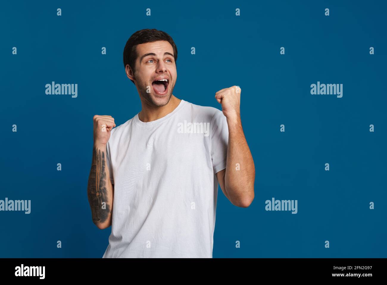 Excited unshaven guy screaming and making winner gesture isolated over ...