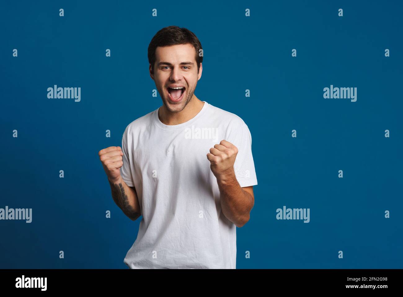 Excited unshaven guy screaming and making winner gesture isolated over ...