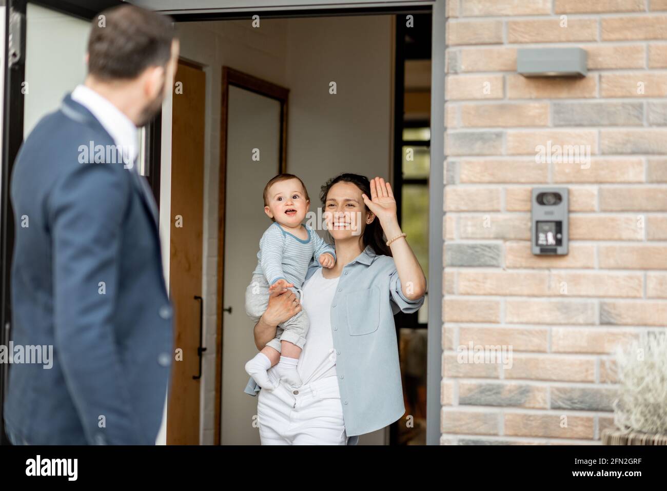 Caucasian Father Waving Goodbye To His Family Before Going To Work Housewife With Newborn Baby caucasian-father-waving-goodbye-to-his-family-before-going-to-work-housewife-with-newborn-baby
