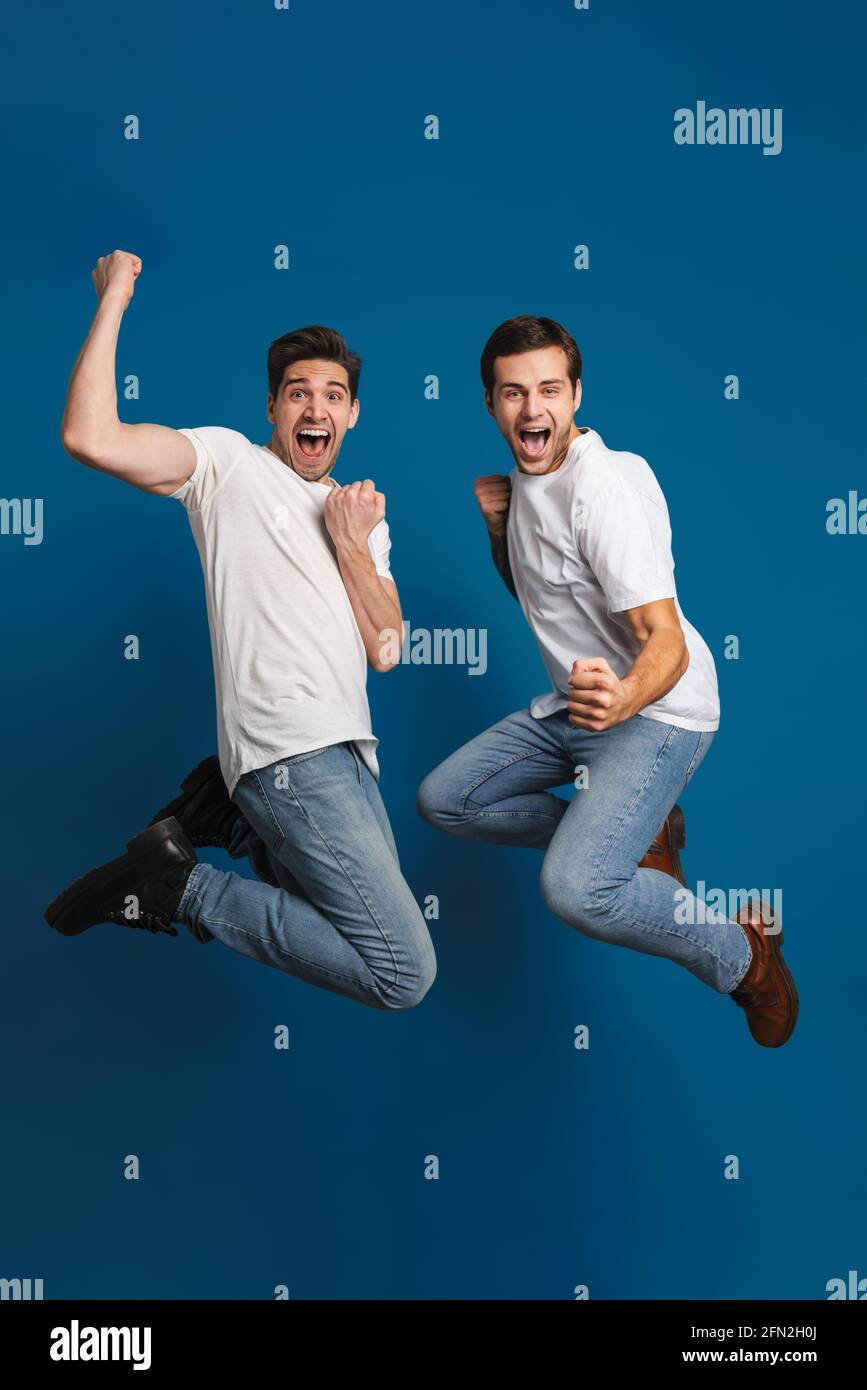 Excited two guys making winner gesture and screaming while jumping ...
