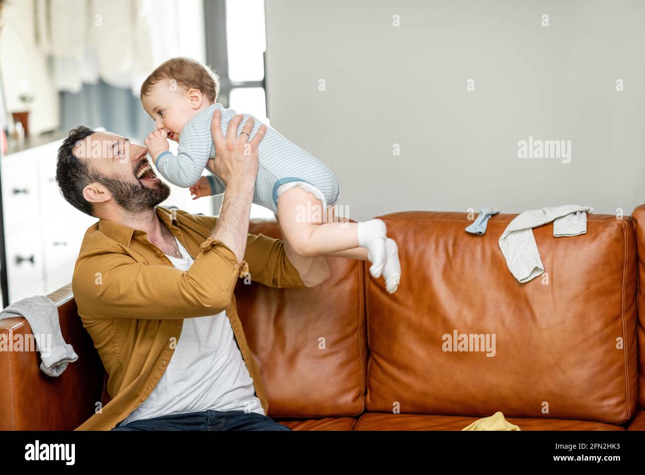 Middle aged dad carrying and playing with newborn baby alone at home ...
