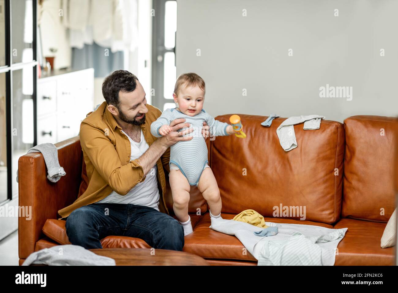 Middle aged dad carrying and playing with newborn baby alone at home ...