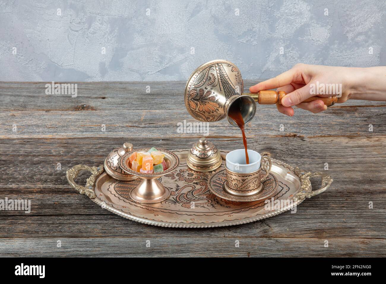 Pouring Turkish coffee into vintage cup on wooden background. Turkish ...