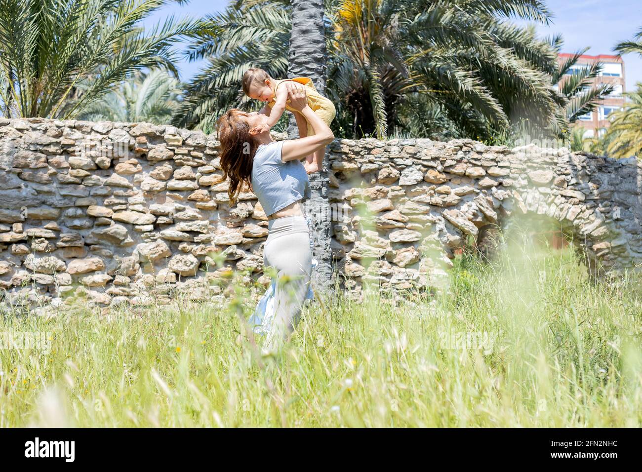 Mom hanging her baby in a park Stock Photo - Alamy