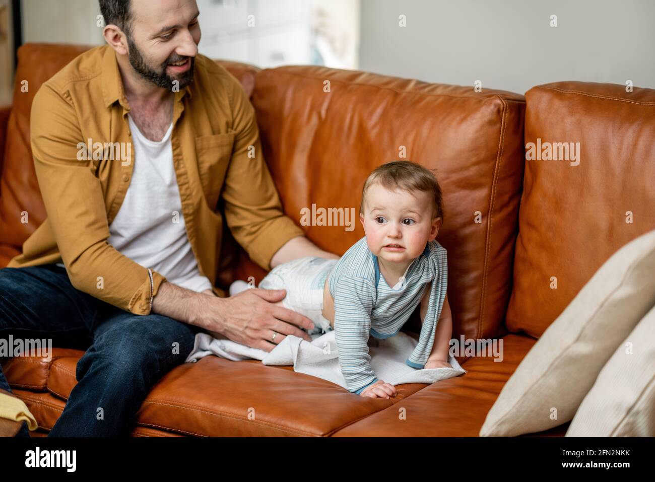 Father changing diaper to his baby son alone at home. Babysitter dad ...