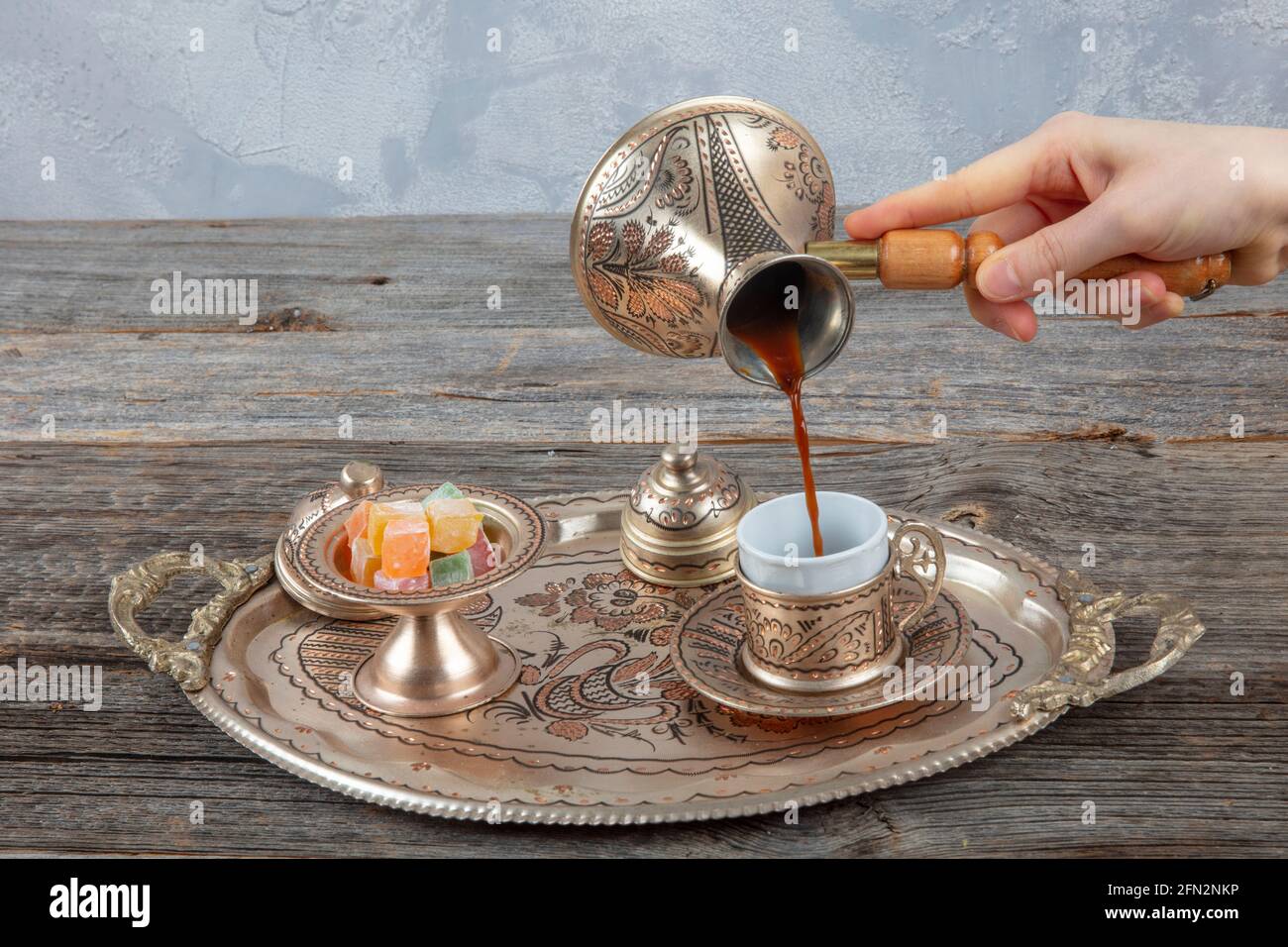 Pouring Turkish coffee into vintage cup on wooden background. Turkish ...