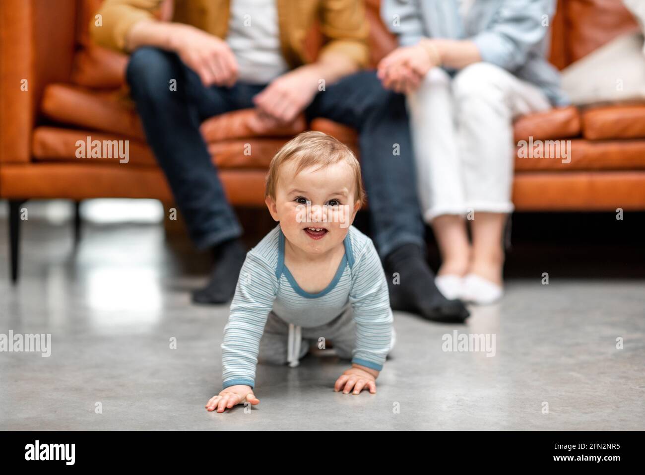 One year baby baby crawling on the floor while father and mother ...