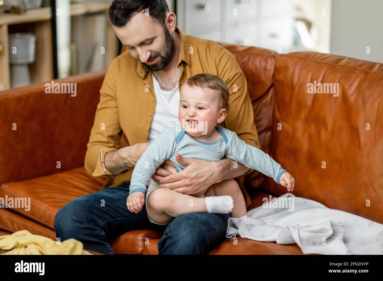 Happy middle aged dad carrying and playing with newborn baby alone at ...