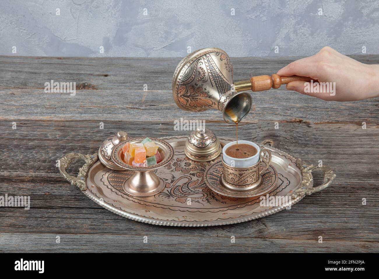 Pouring Turkish coffee into vintage cup on wooden background. Turkish ...