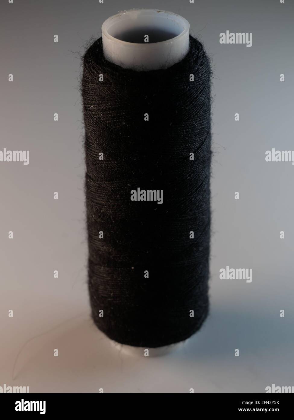 Vertical shot of a black sewing thread Stock Photo - Alamy
