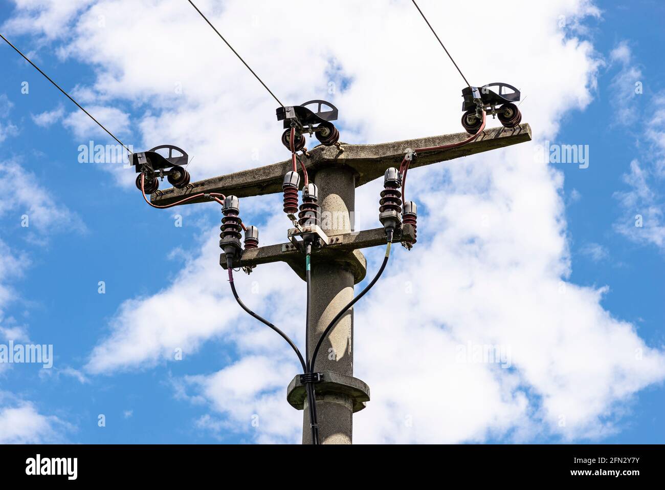 Concrete electric pole with ceramic insulators and voltage lines, in ...
