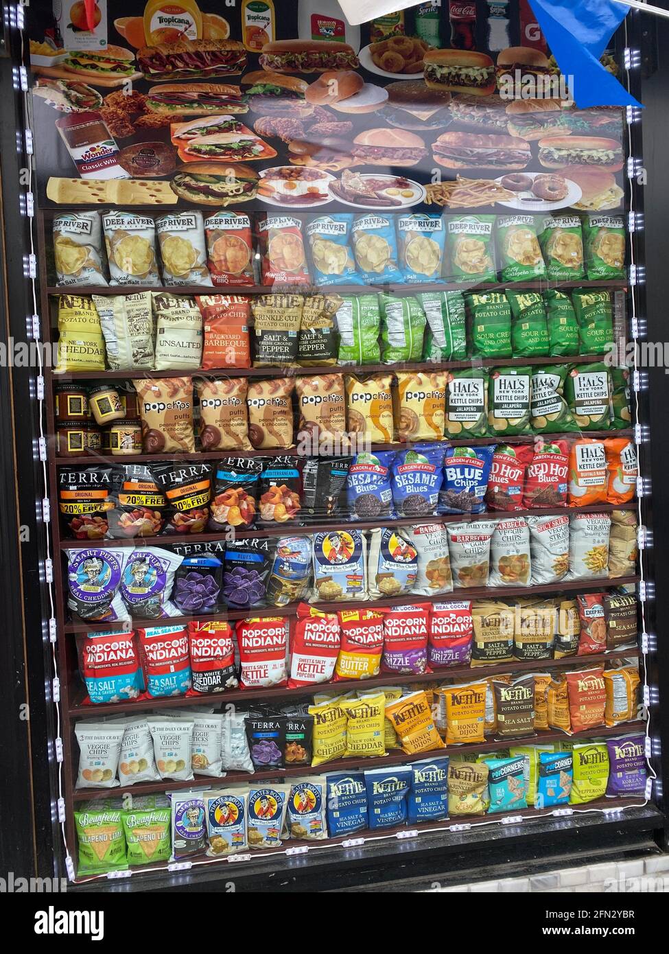 Deli-grocery window displaying a variety of brands of chips a most ...