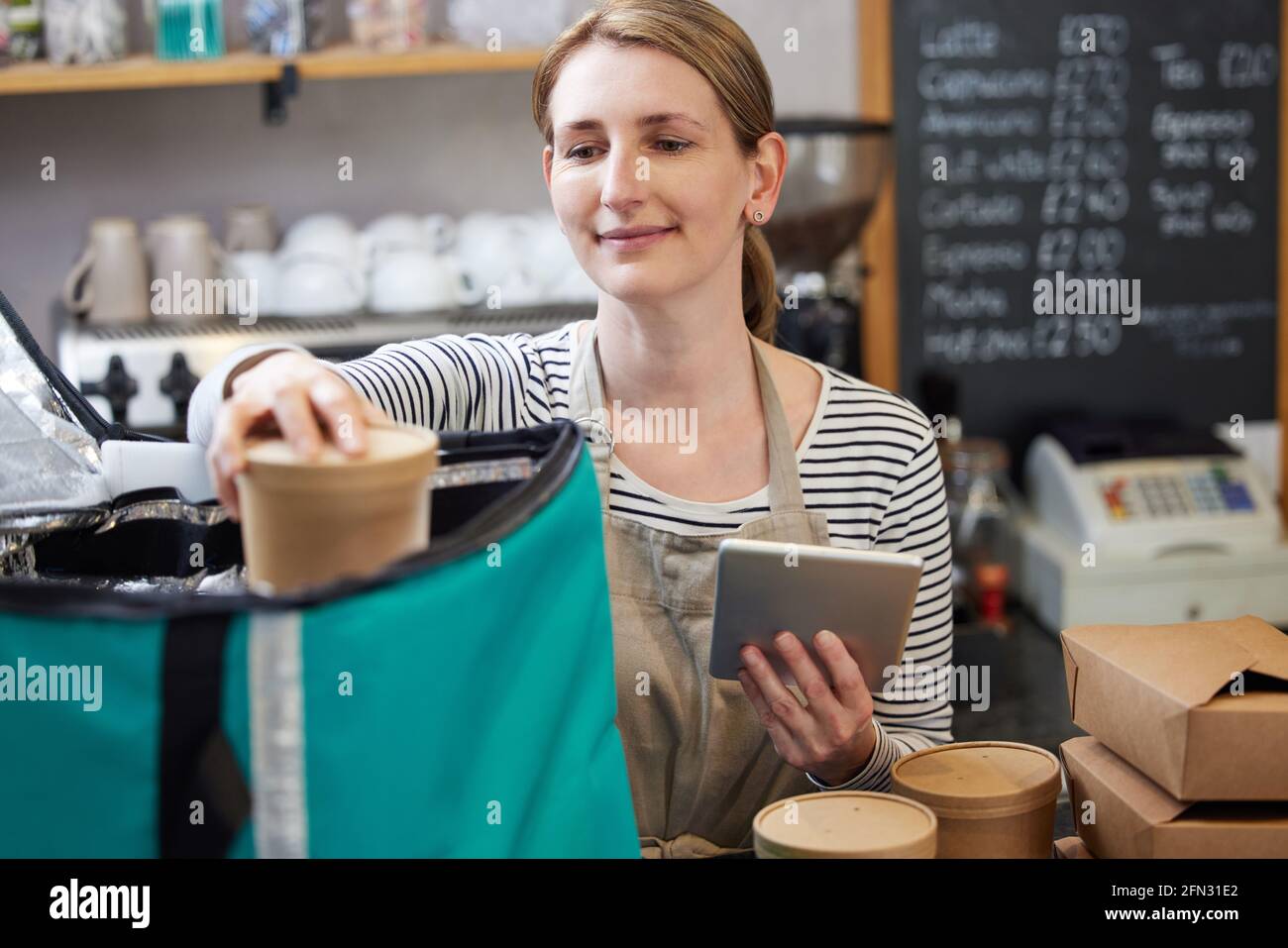 Female Restaurant Worker With Digital Tablet Packing Insulated Bag For ...