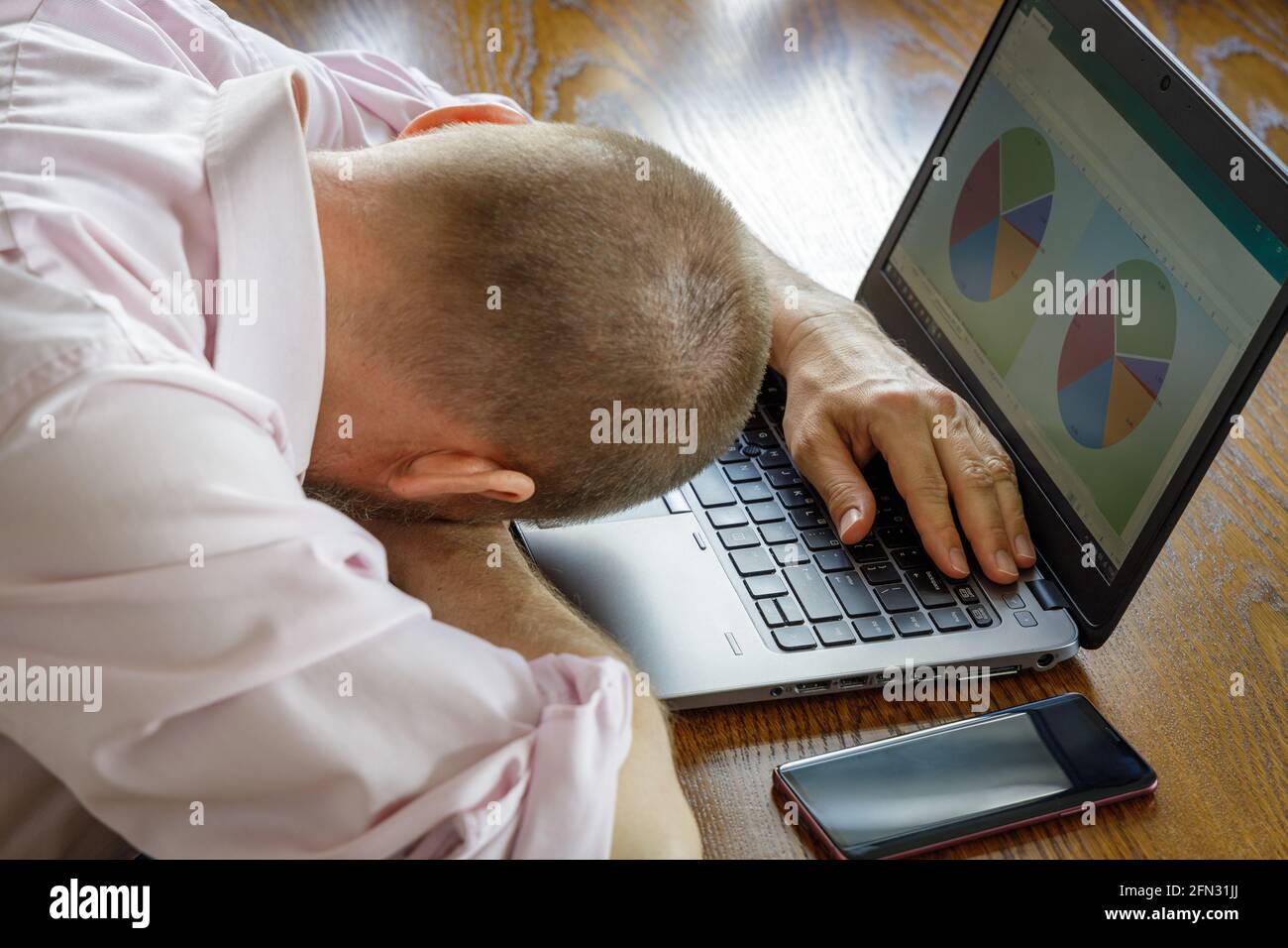 Tired office worker forking from home, having his nap by the laptop ...