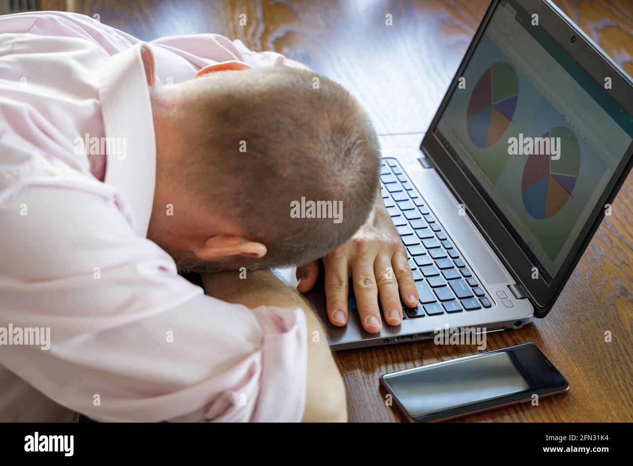 Tired office worker forking from home, having his nap by the laptop ...
