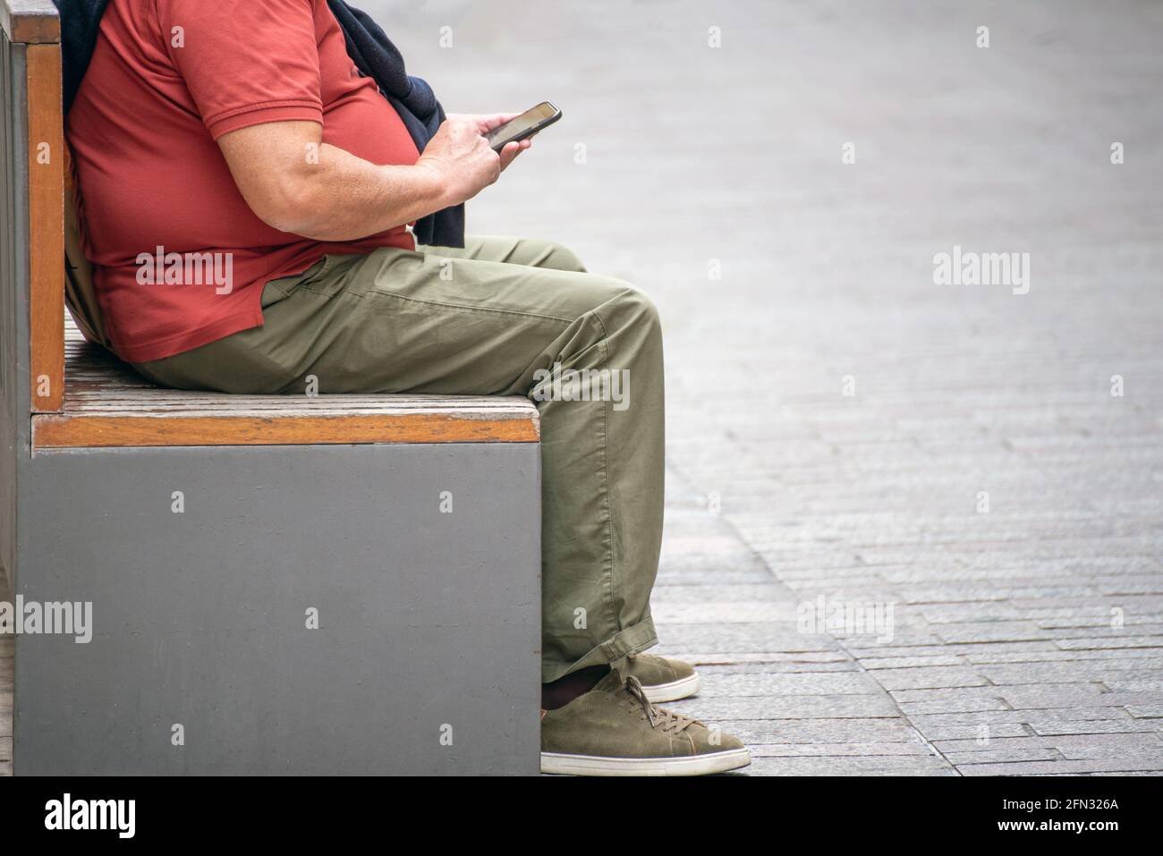 Poor man sitting on street bench handling a mobile phone Stock Photo ...