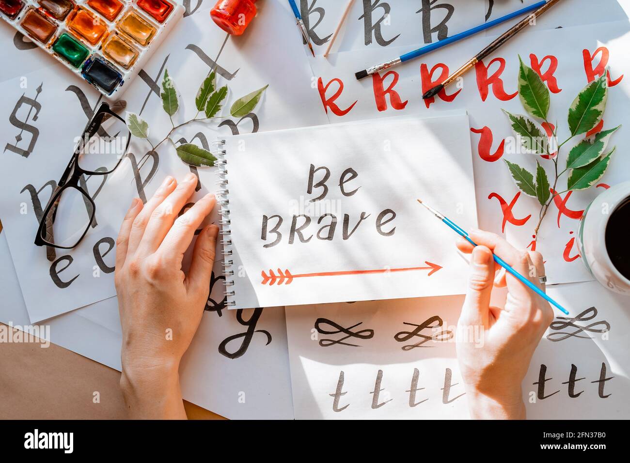 Overhead view on male man hands calligraphy sheets, nibs, paper, ink ...