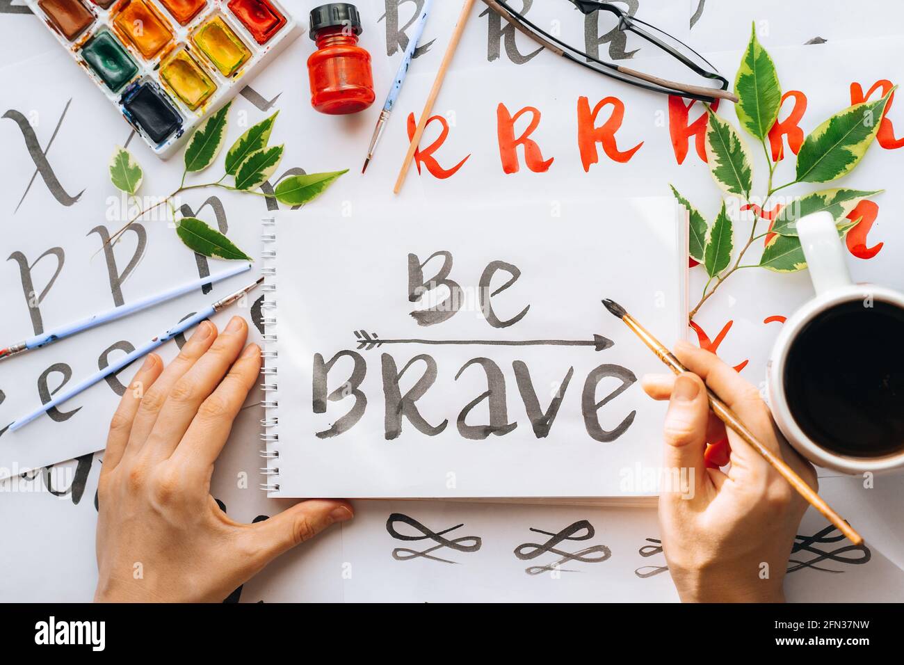 Overhead view on male man hands calligraphy sheets, nibs, paper, ink ...